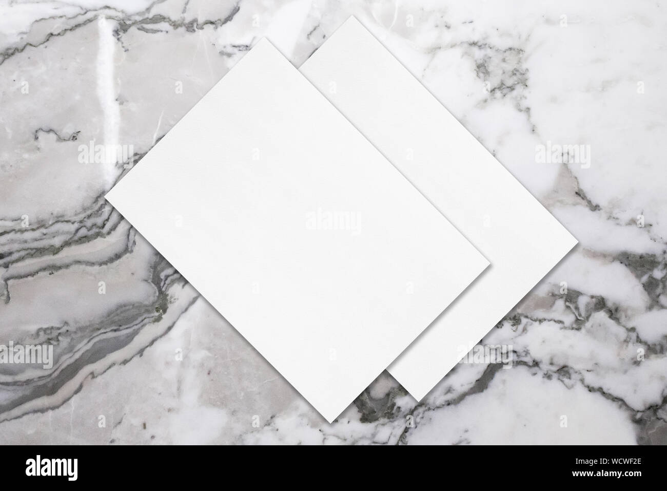 Two empty white rectangle poster mockups lying diagonally on top of ...