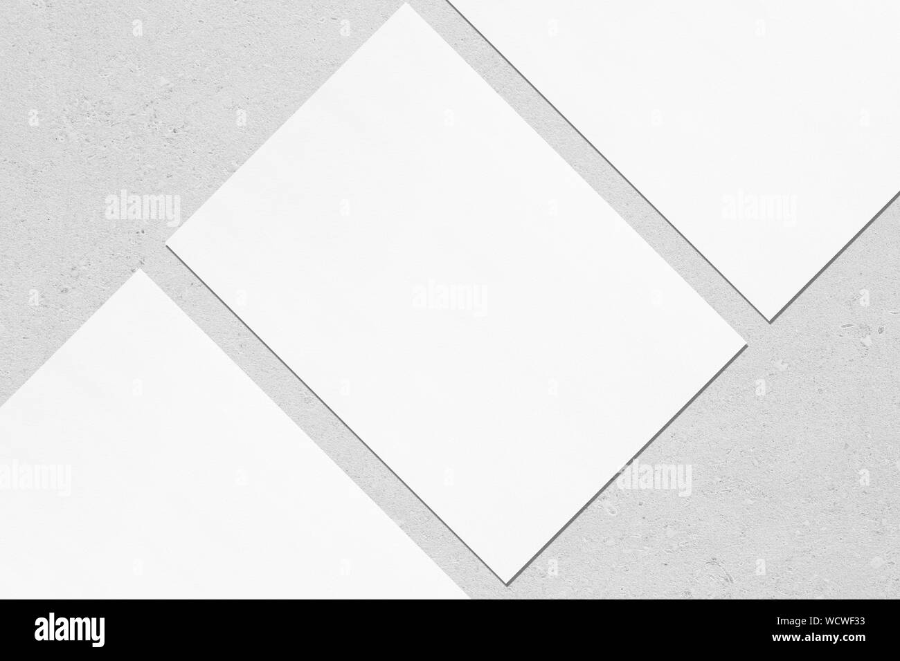 Closeup of three empty white rectangle poster mockups lying diagonally ...