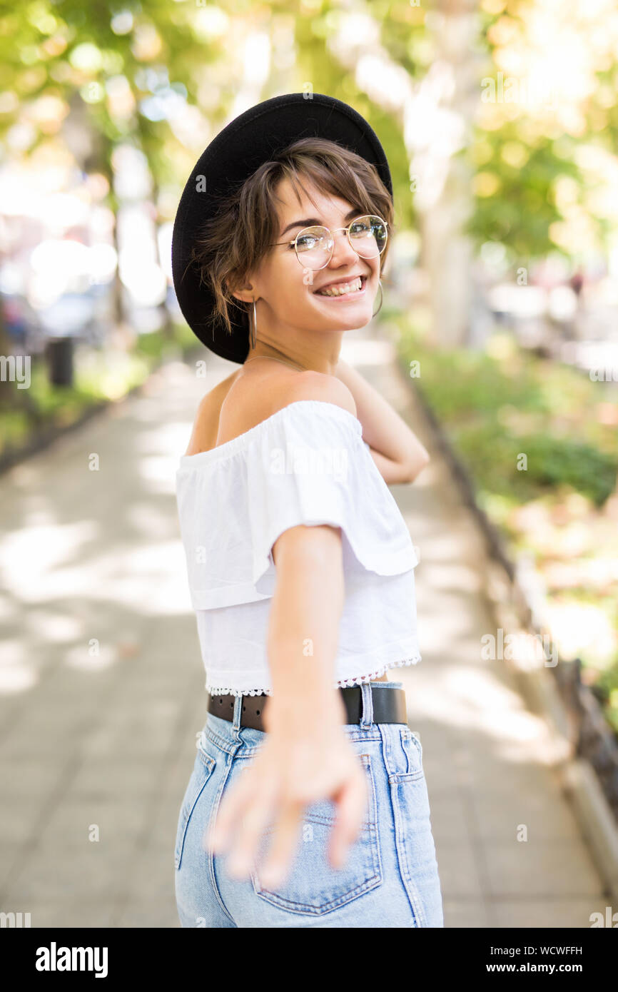 Smiling young woman walking outdoors, waving her hand Stock Photo - Alamy