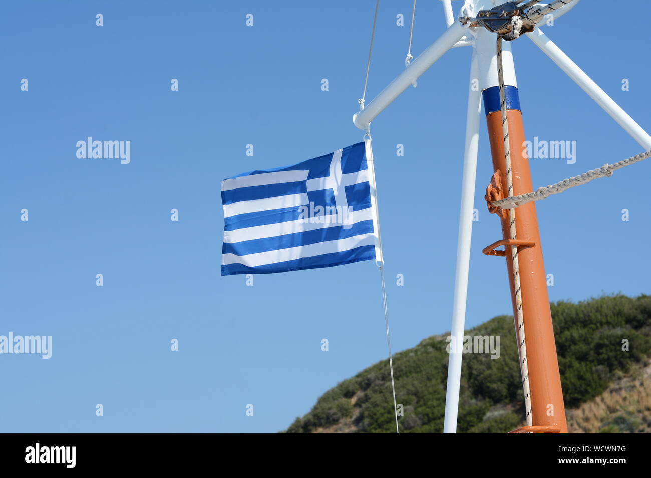 Greek flag on the mast of a sailing boat. Travelling in the blue sea ...