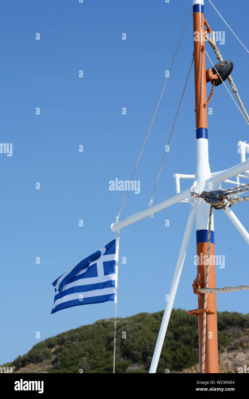 Greek flag on the mast of a sailing boat. Travelling in the blue sea ...