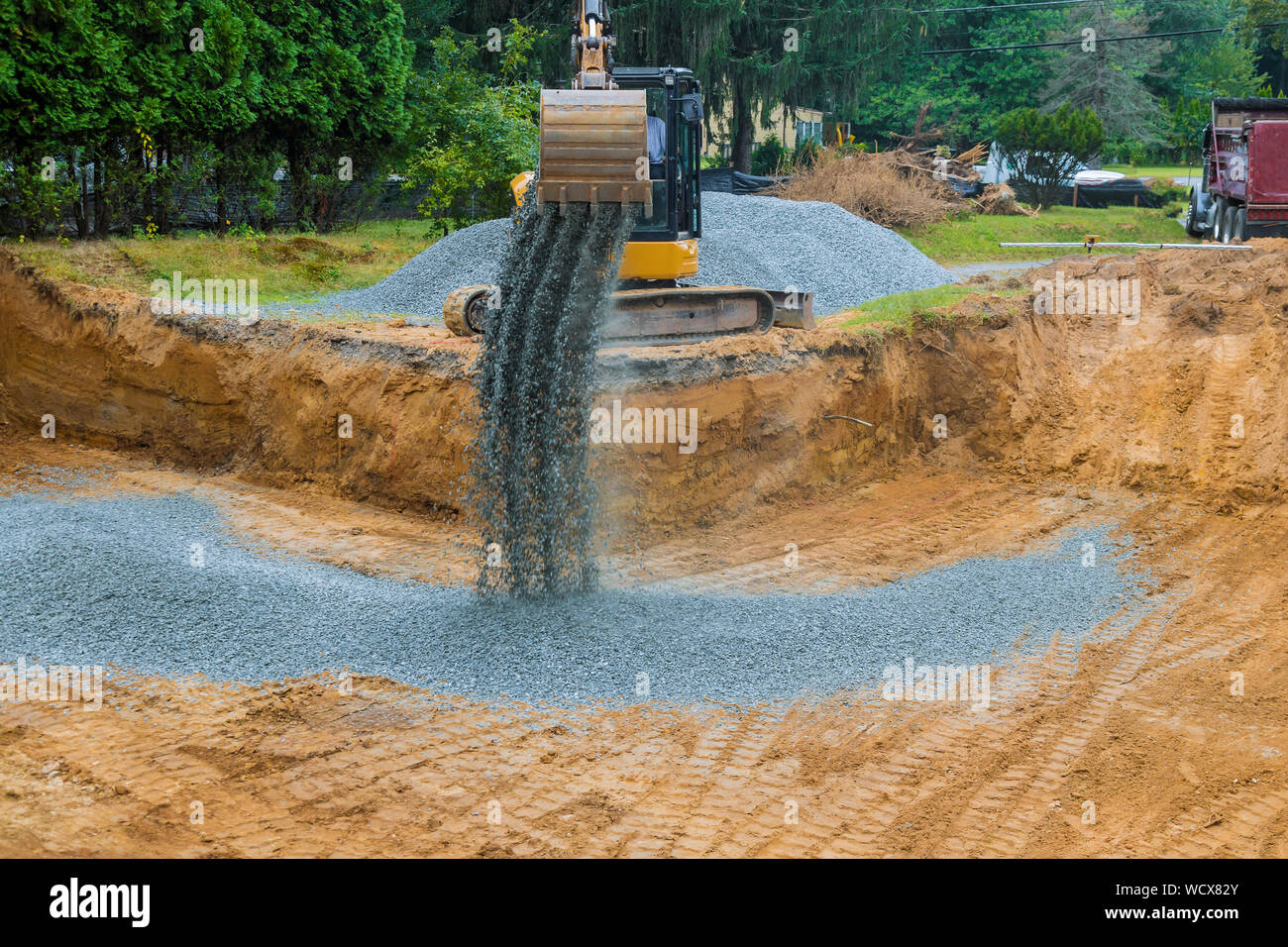The excavator wheel during backfilling gravel around the foundation for ...