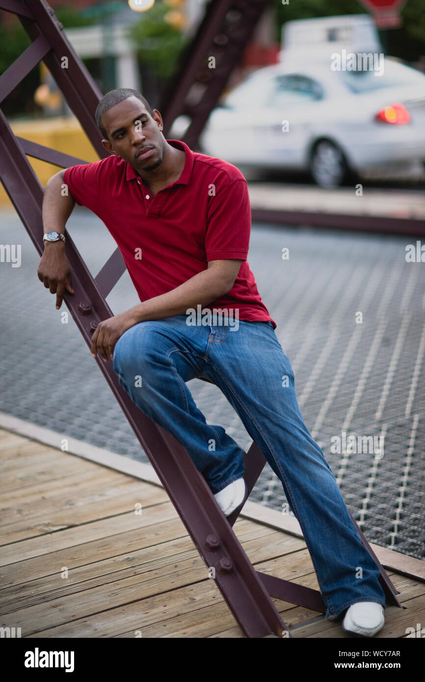 Serious young man leaning against a steel beam on a city street Stock ...