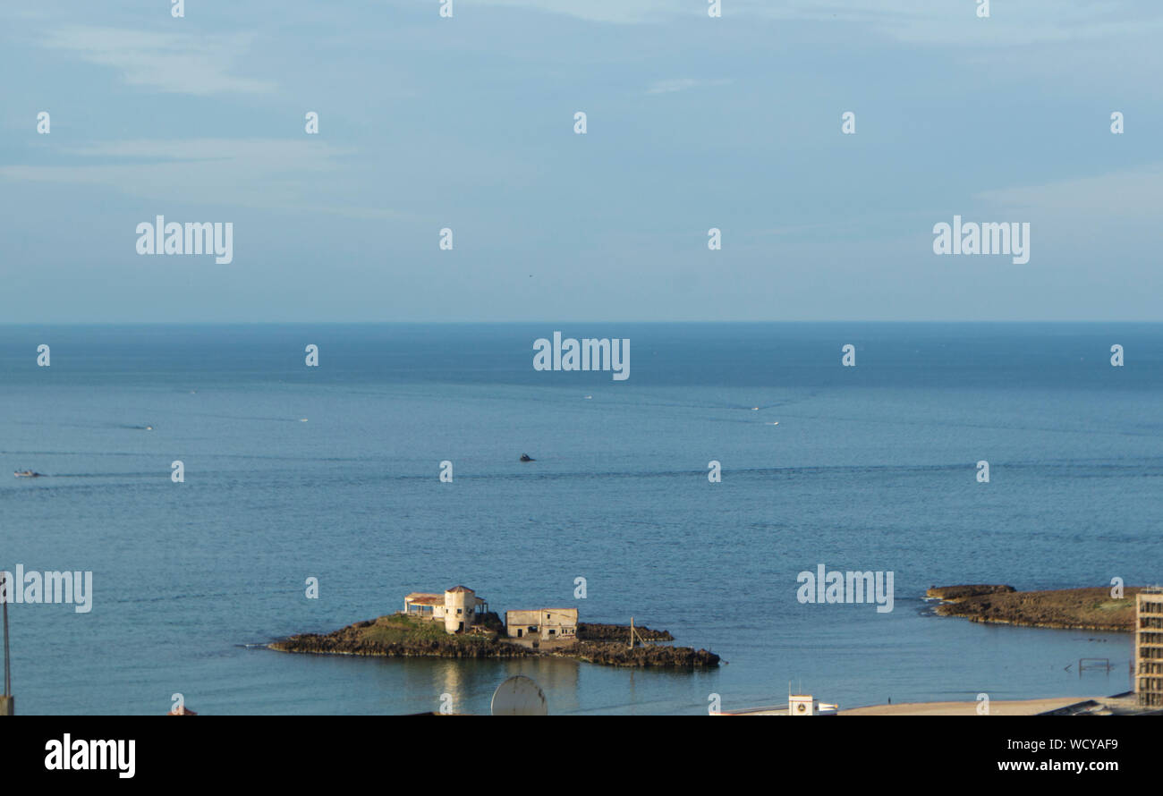 A view over the sea and a little island with a house in ruins. ElKala ...