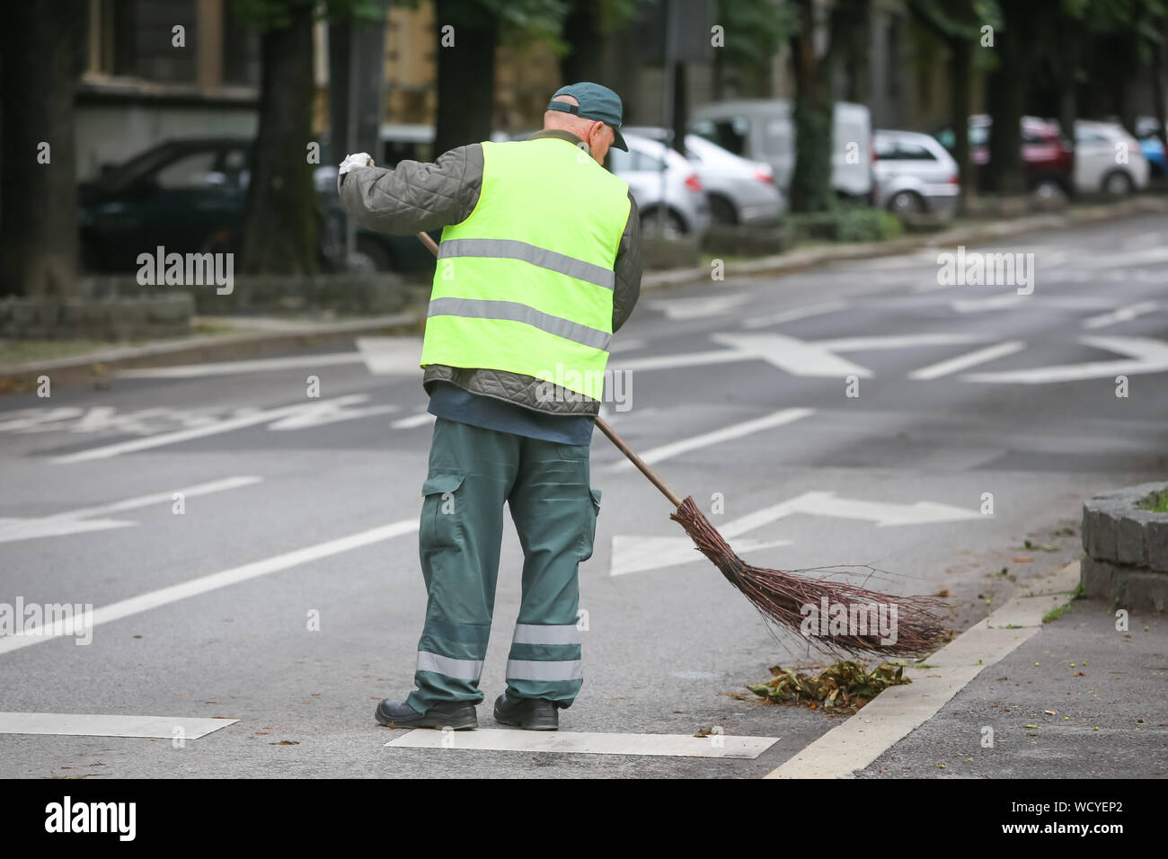 Garbage man brooming the leaves on the street of the city Stock Photo ...