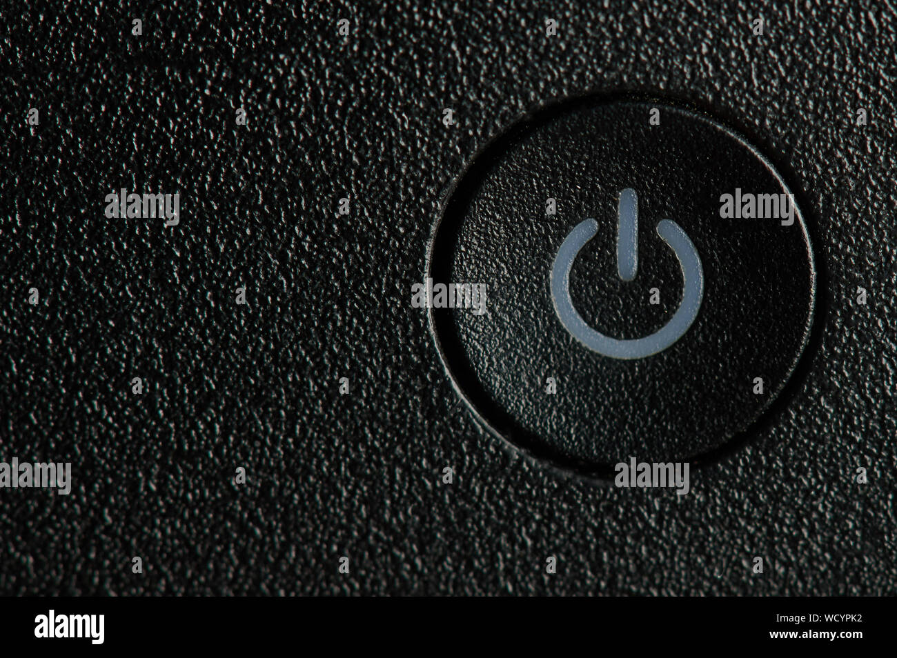 One round power on and off button on rough black plastic background ...
