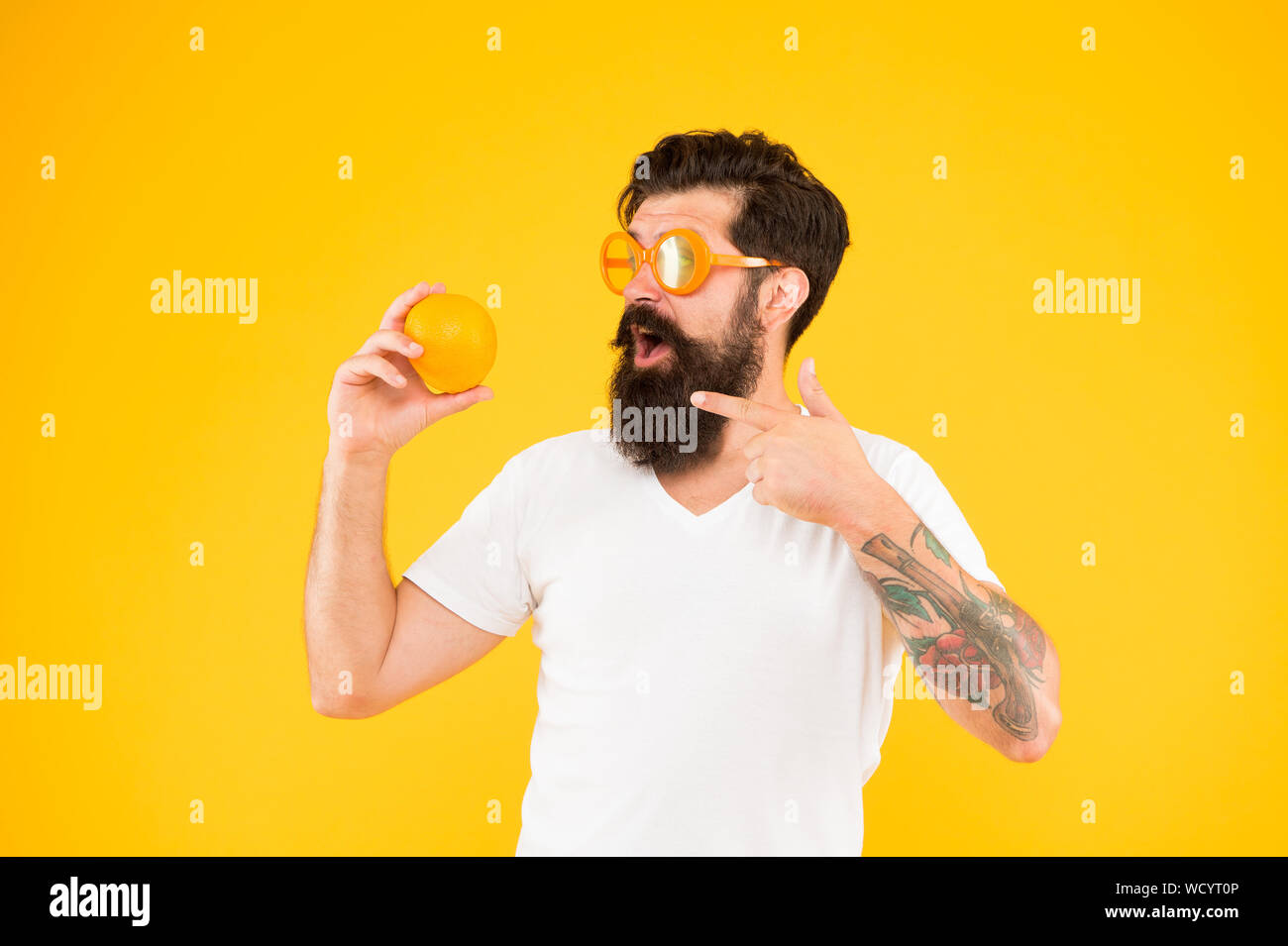 A citrus food. Hipster pointing finger at vitamin food on yellow ...