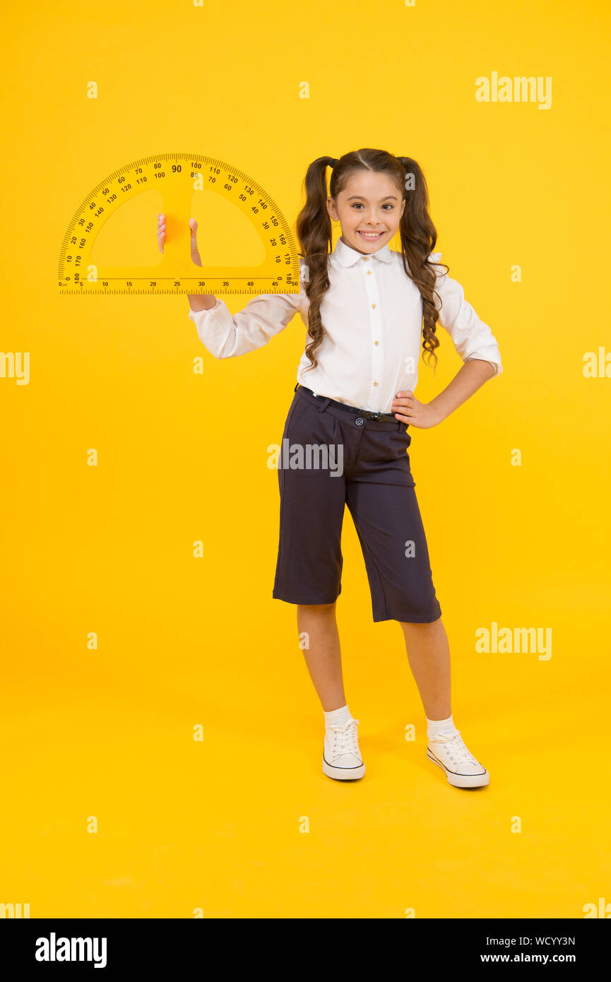 Doing well at maths. Cute little schoolgirl holding measuring tool for ...