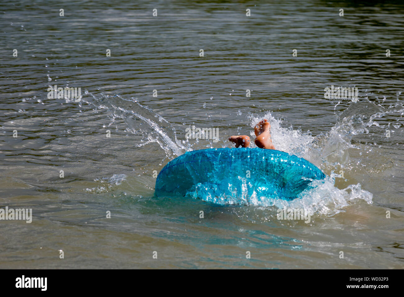 A swimmer's feet appear above the surface of the water as her tube ...
