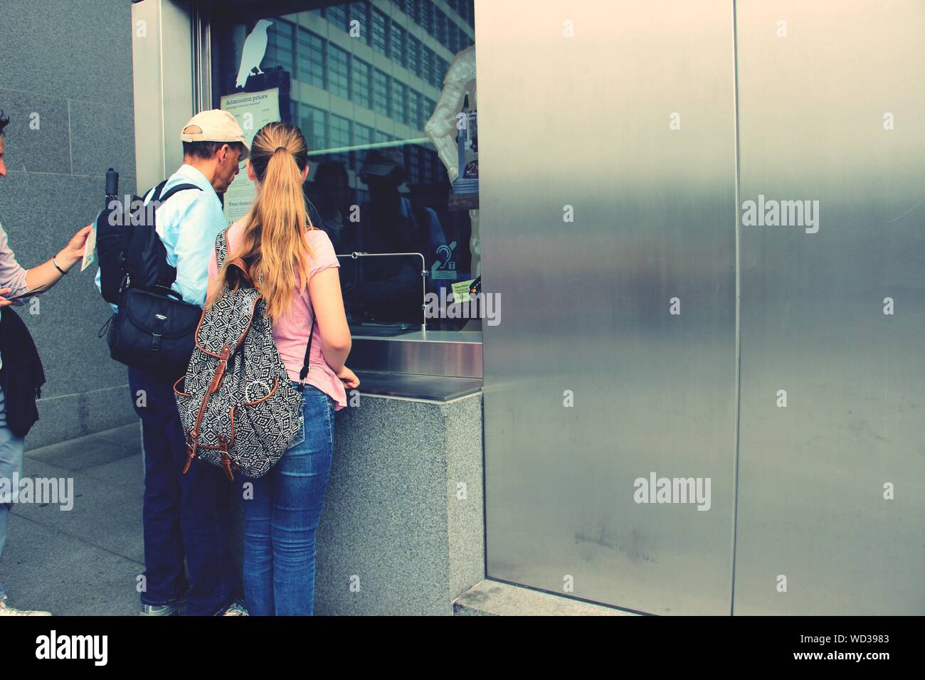 Rear View Of People Standing At Ticket Counter Stock Photo - Alamy