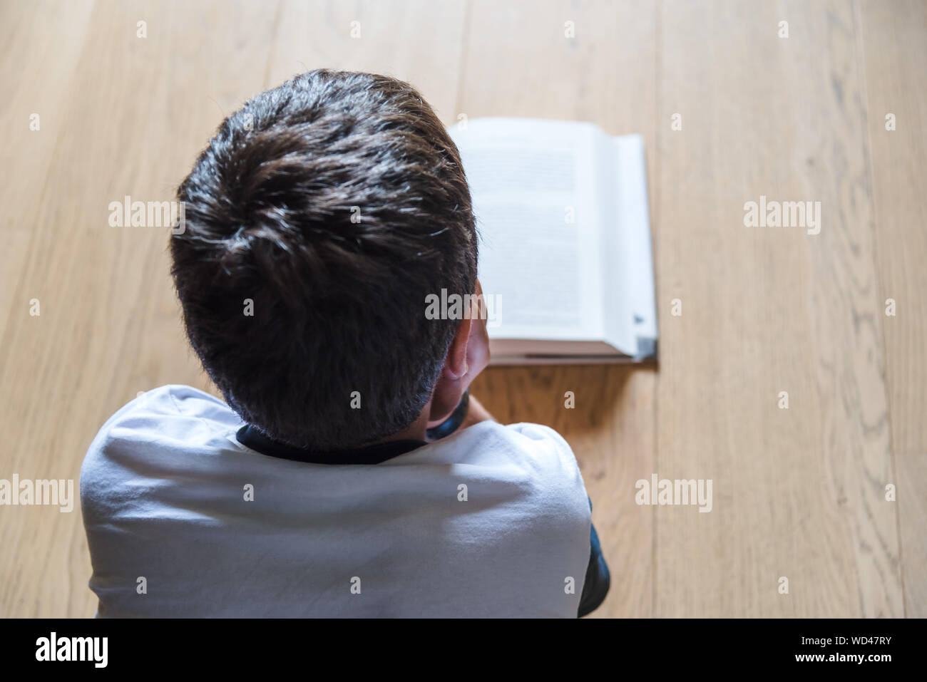 Boy sitting on floor reading book hi-res stock photography and images ...