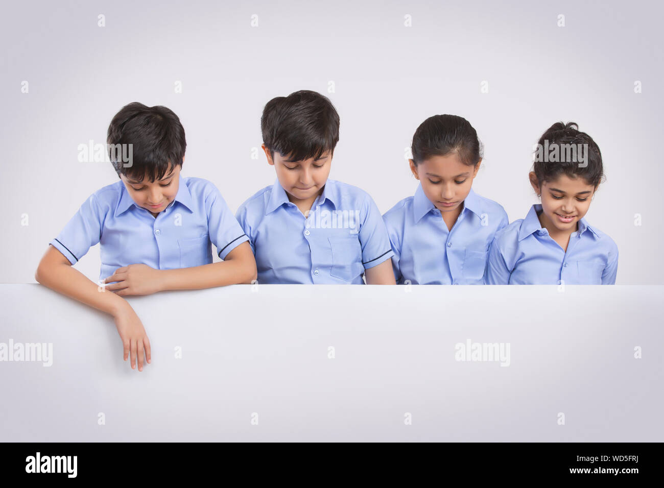 portrait of school children looking down at something Stock Photo - Alamy