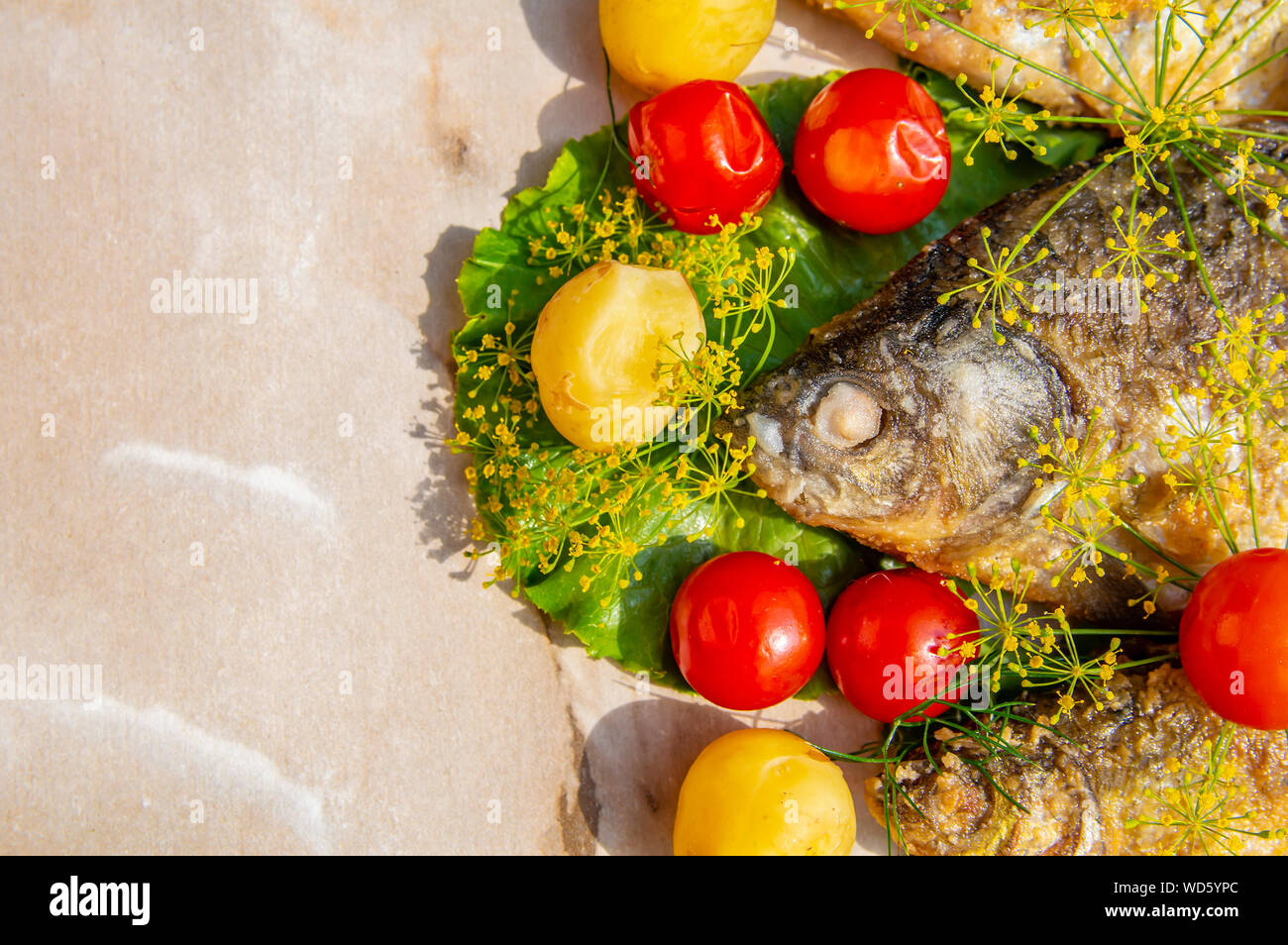 Fried crucian fish on a light background with vegetables and lemon ...