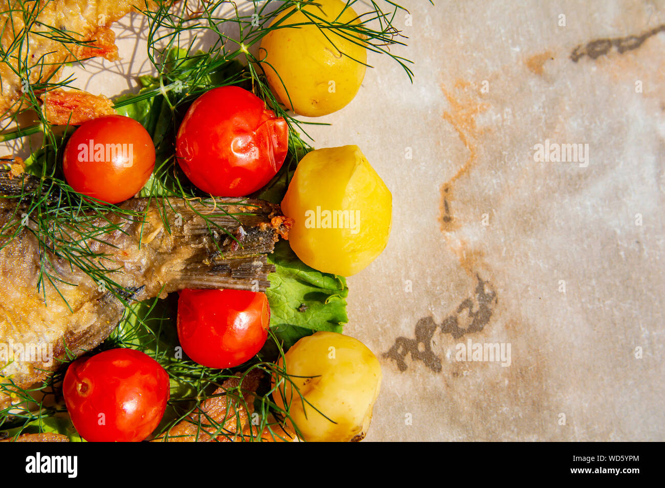 Fried crucian fish on a light background with vegetables and lemon ...