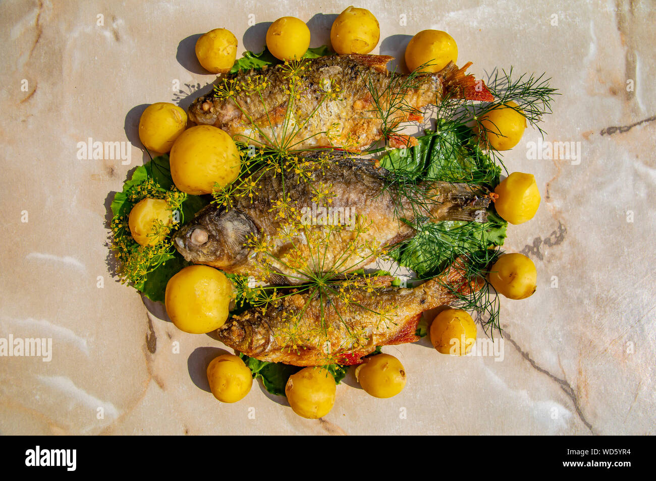 Fried crucian fish on a light background with vegetables and lemon ...