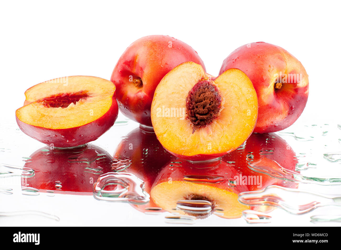 Whole peaches and two halves of a peach with a stone inside on a white ...