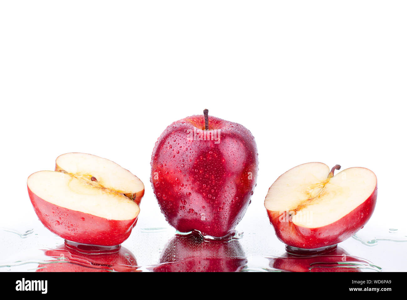 One whole red apple and two halves of apple in water drops on mirror ...