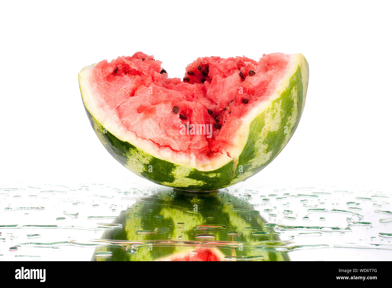 Half watermelon on a white mirror background in water droplets isolated ...