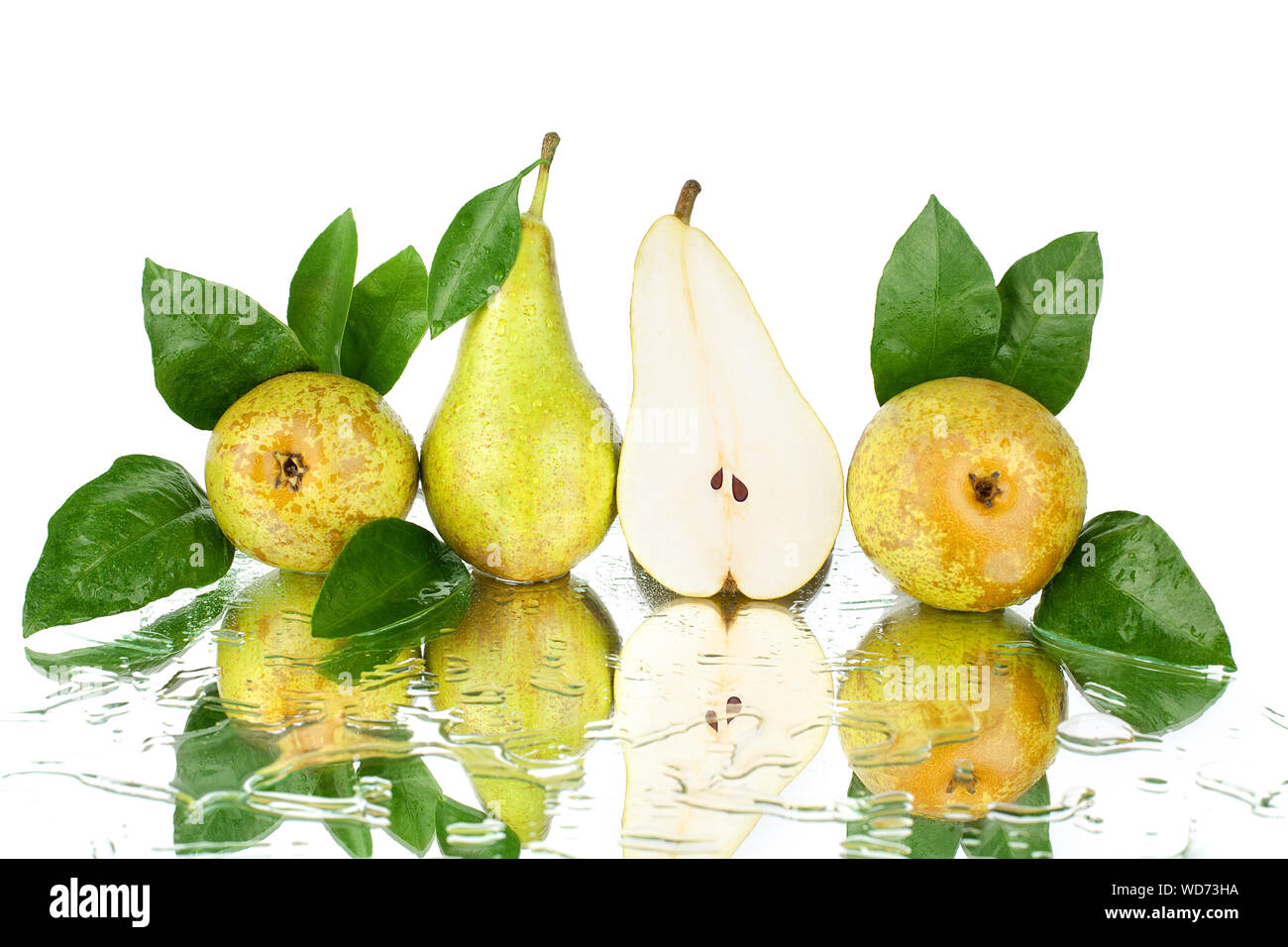 Pears with green leaves and cut half of pear with seeds on white mirror ...