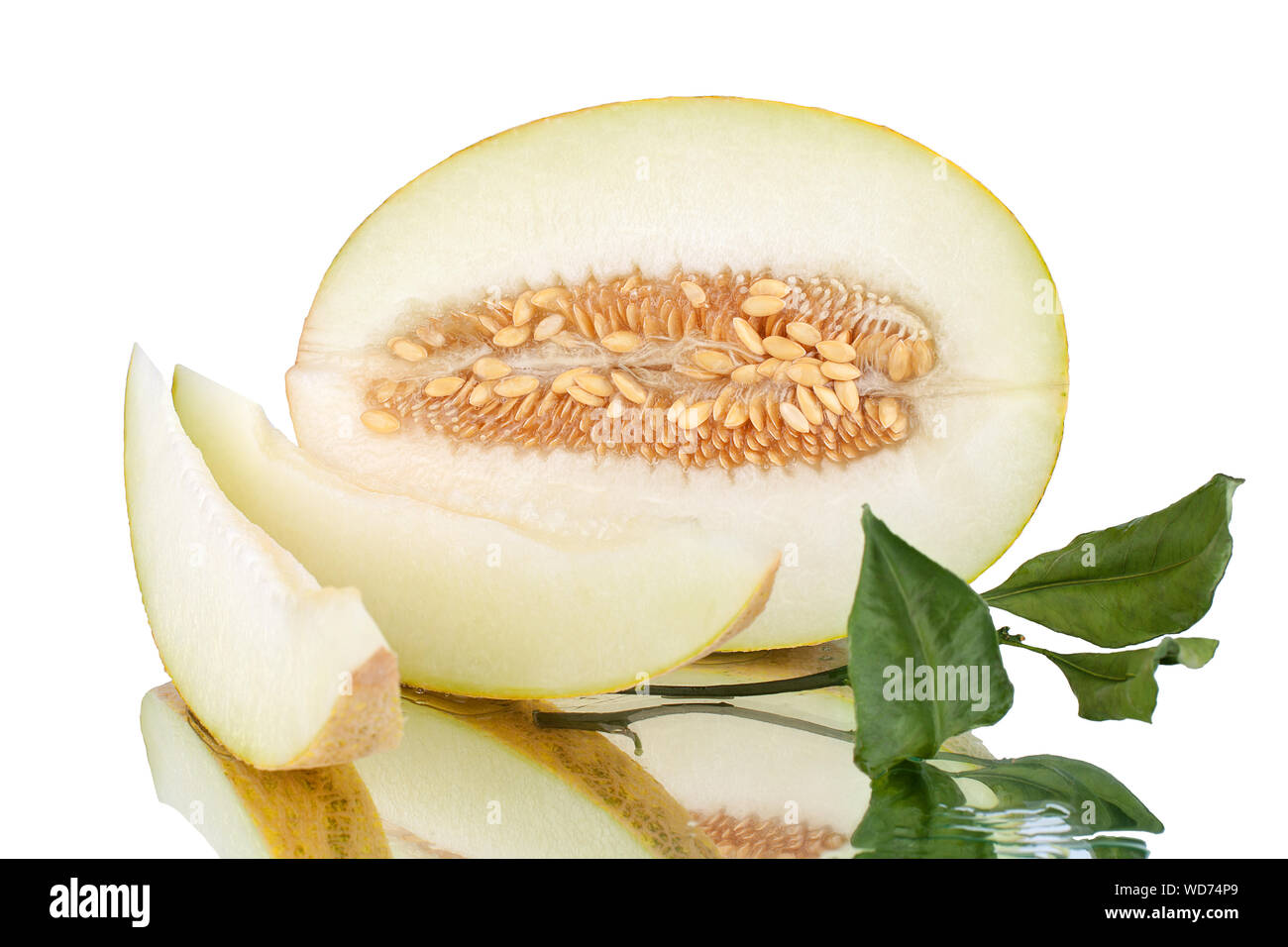 Half melon with seeds, melon slices and green leaves on white mirror ...