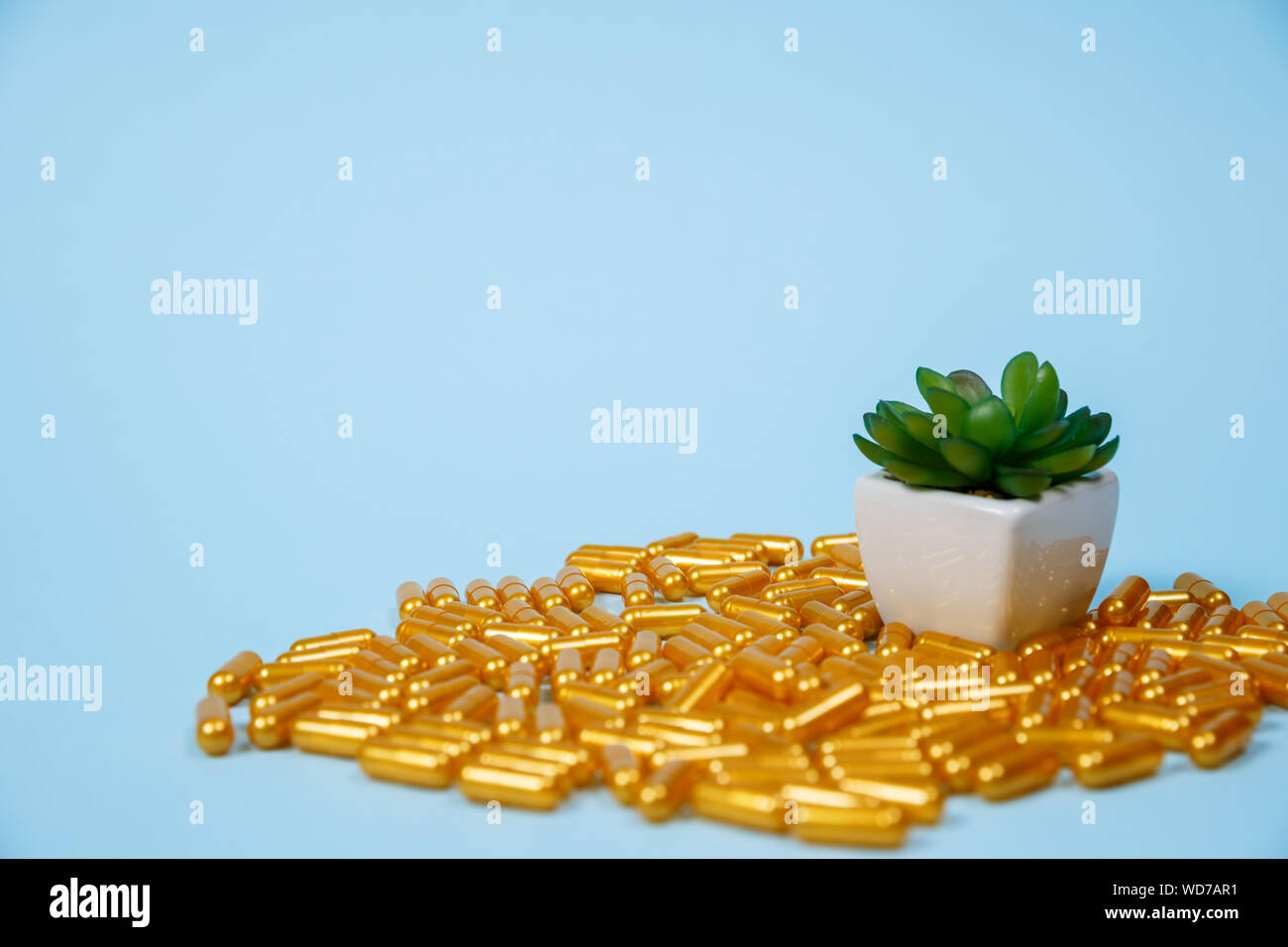 Golden pill capsules on blue background Stock Photo - Alamy