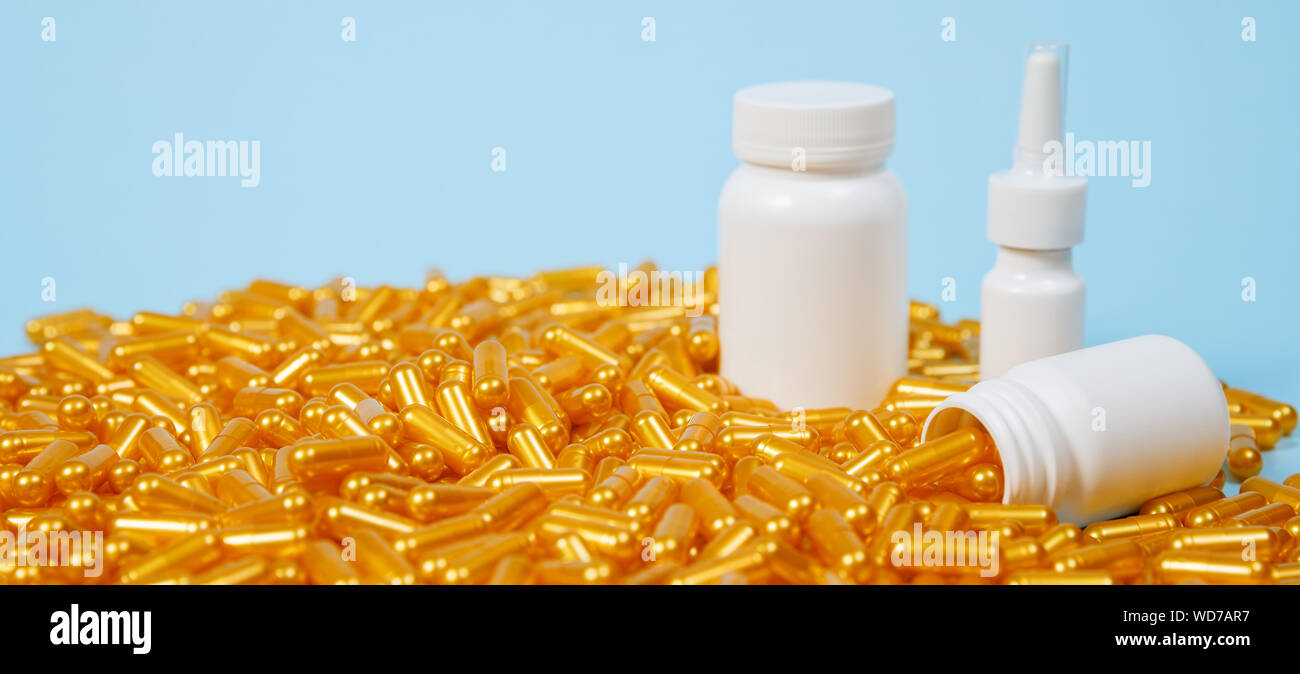 Golden pill capsules on blue background Stock Photo - Alamy