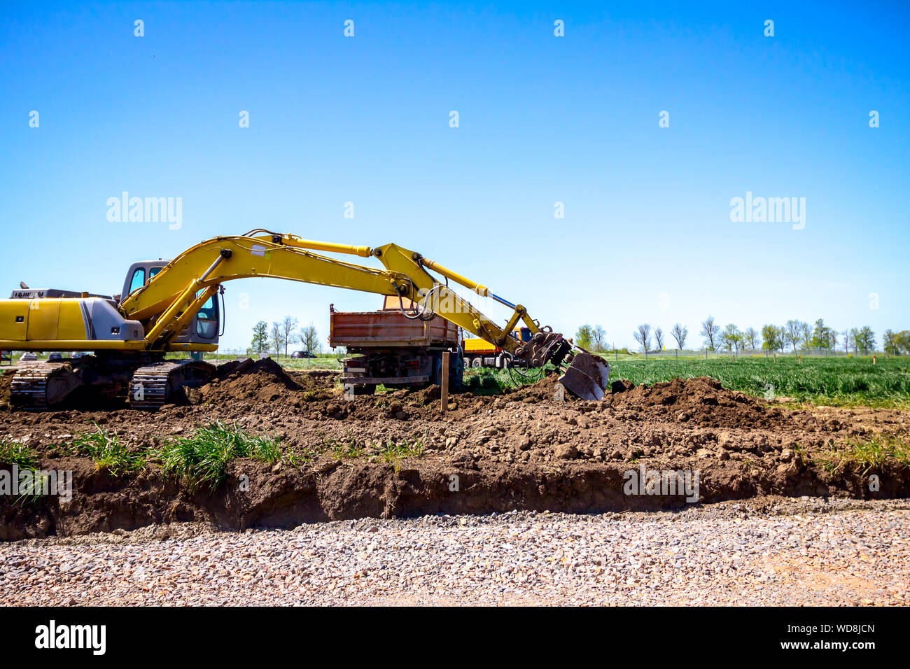 Big excavator is filling a dumper truck with soil at construction site ...