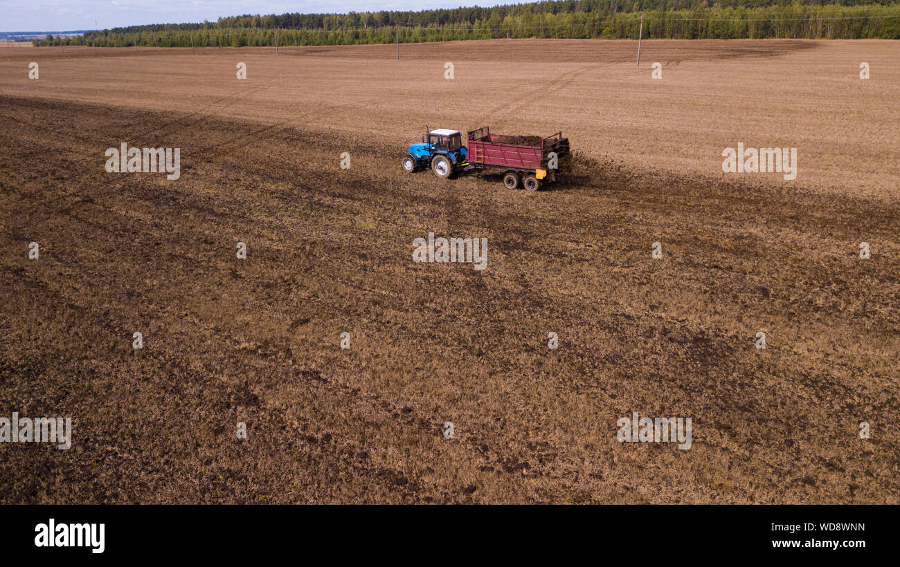 tractor scatters manure on the field aerial photography from a drone ...