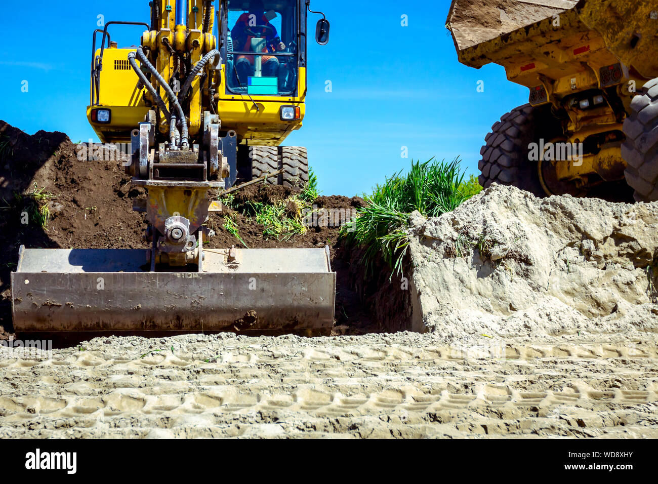 Big excavator is filling a dumper truck with soil at construction site ...