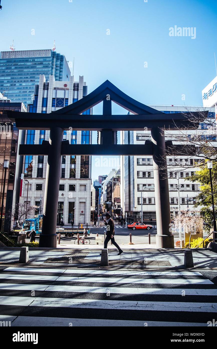 Vertical shot of a person walking near a gate surrounded by high rise ...