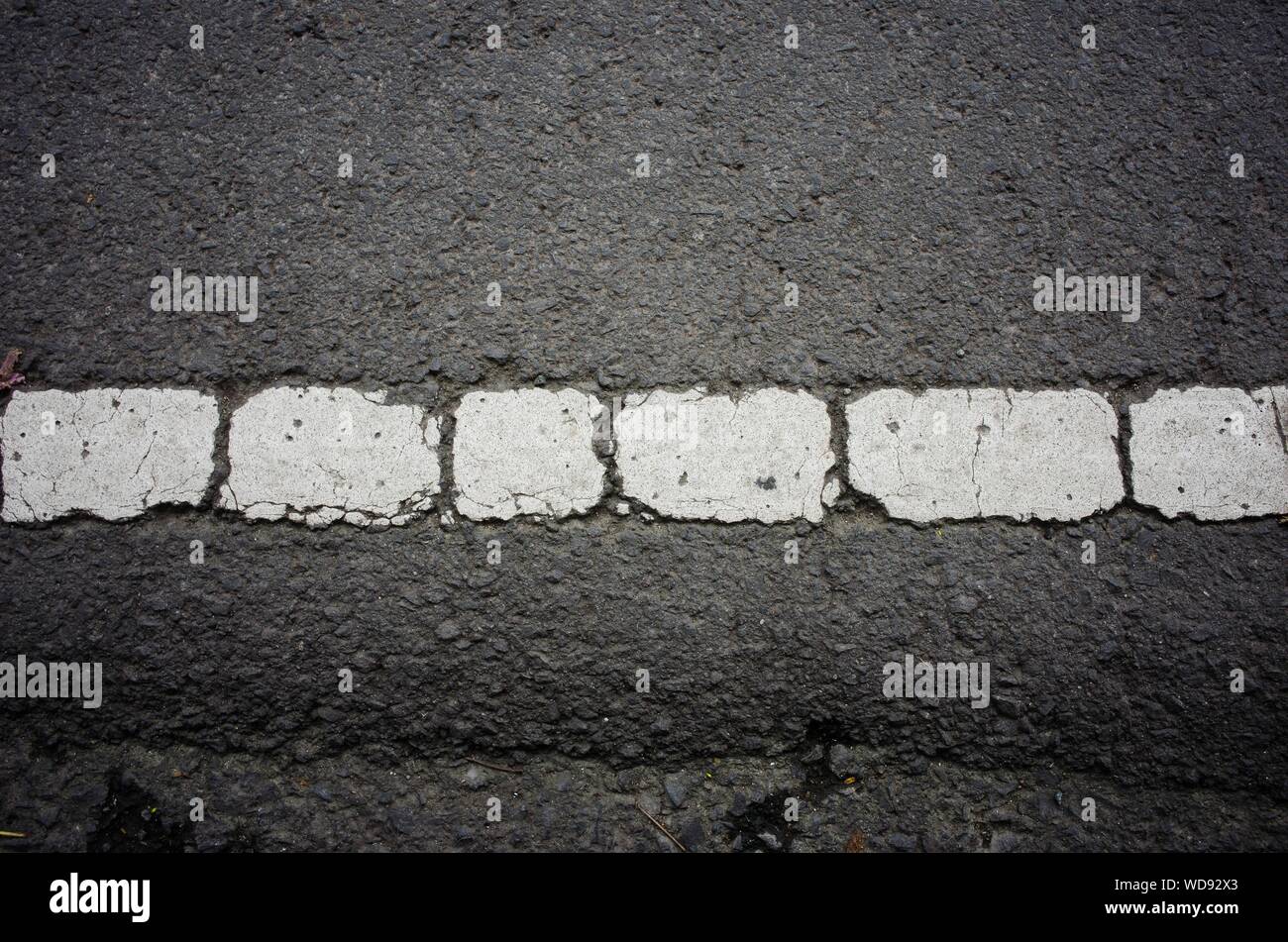 Concrete road with a weathered white line on it Stock Photo - Alamy