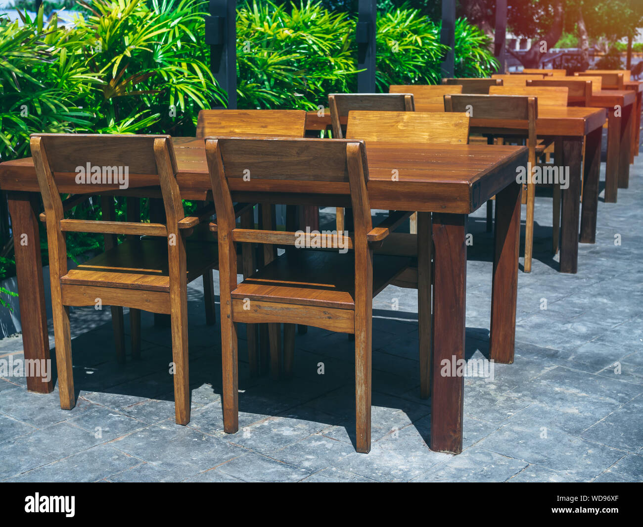 Empty wooden dining table set near the green garden Stock Photo - Alamy