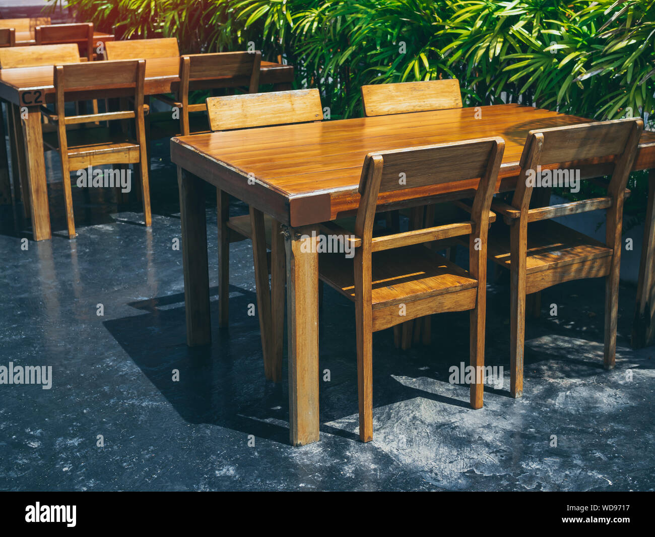 Empty wooden dining table set near the green garden Stock Photo - Alamy