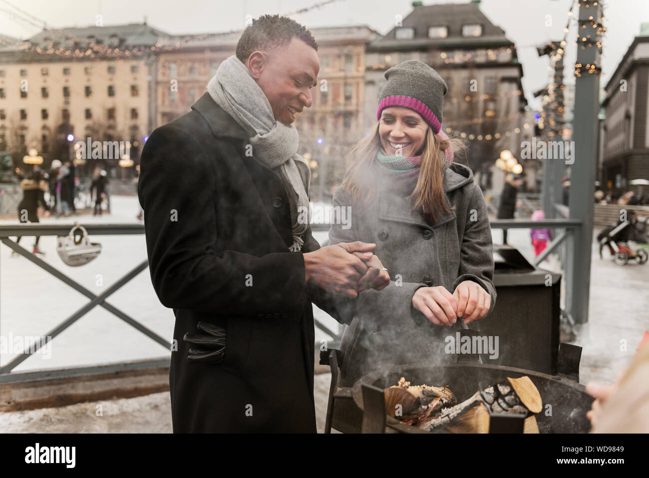 Couple warming their hands over fire Stock Photo - Alamy