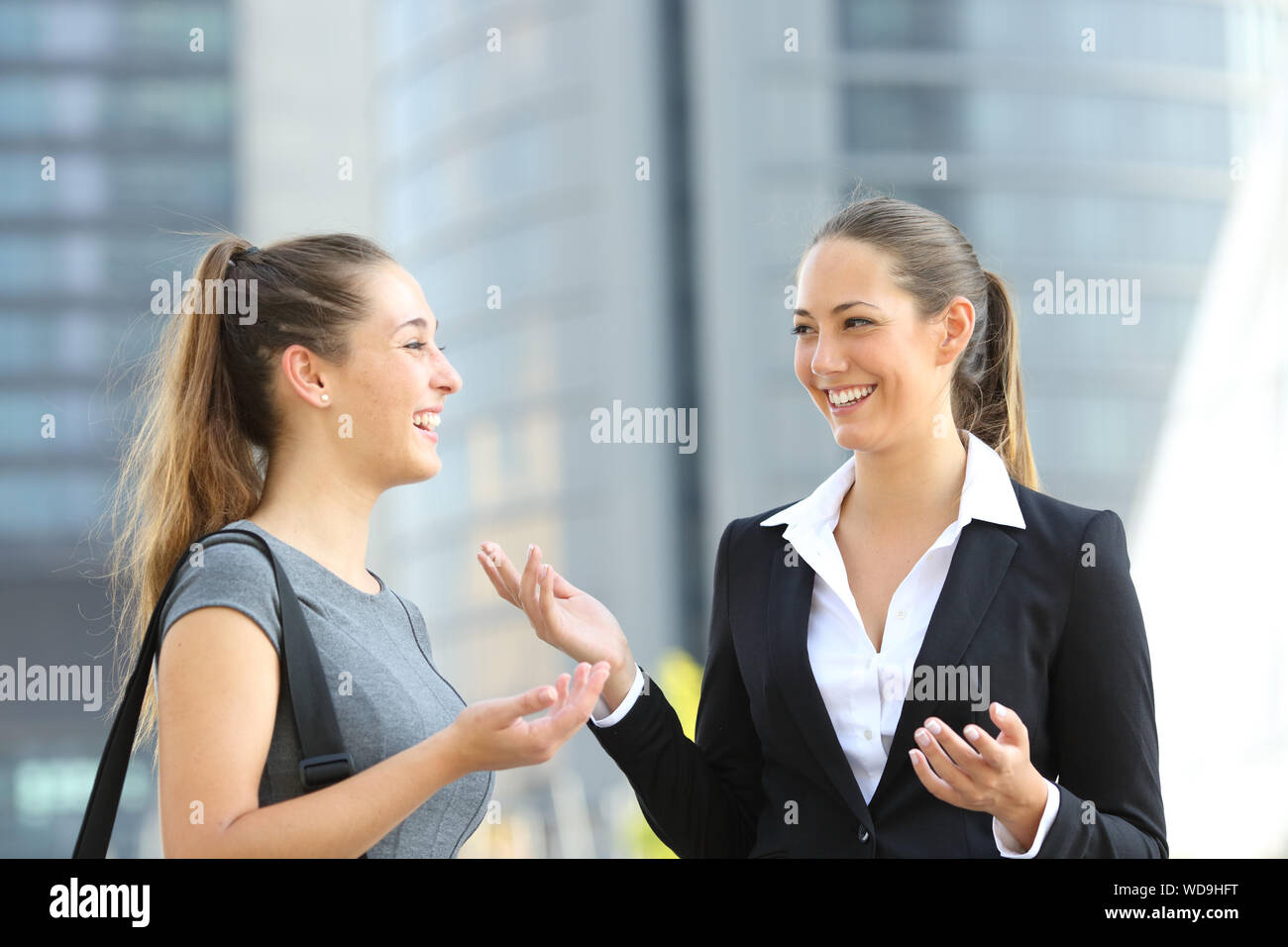 Two office employees talking standing in the street with office ...