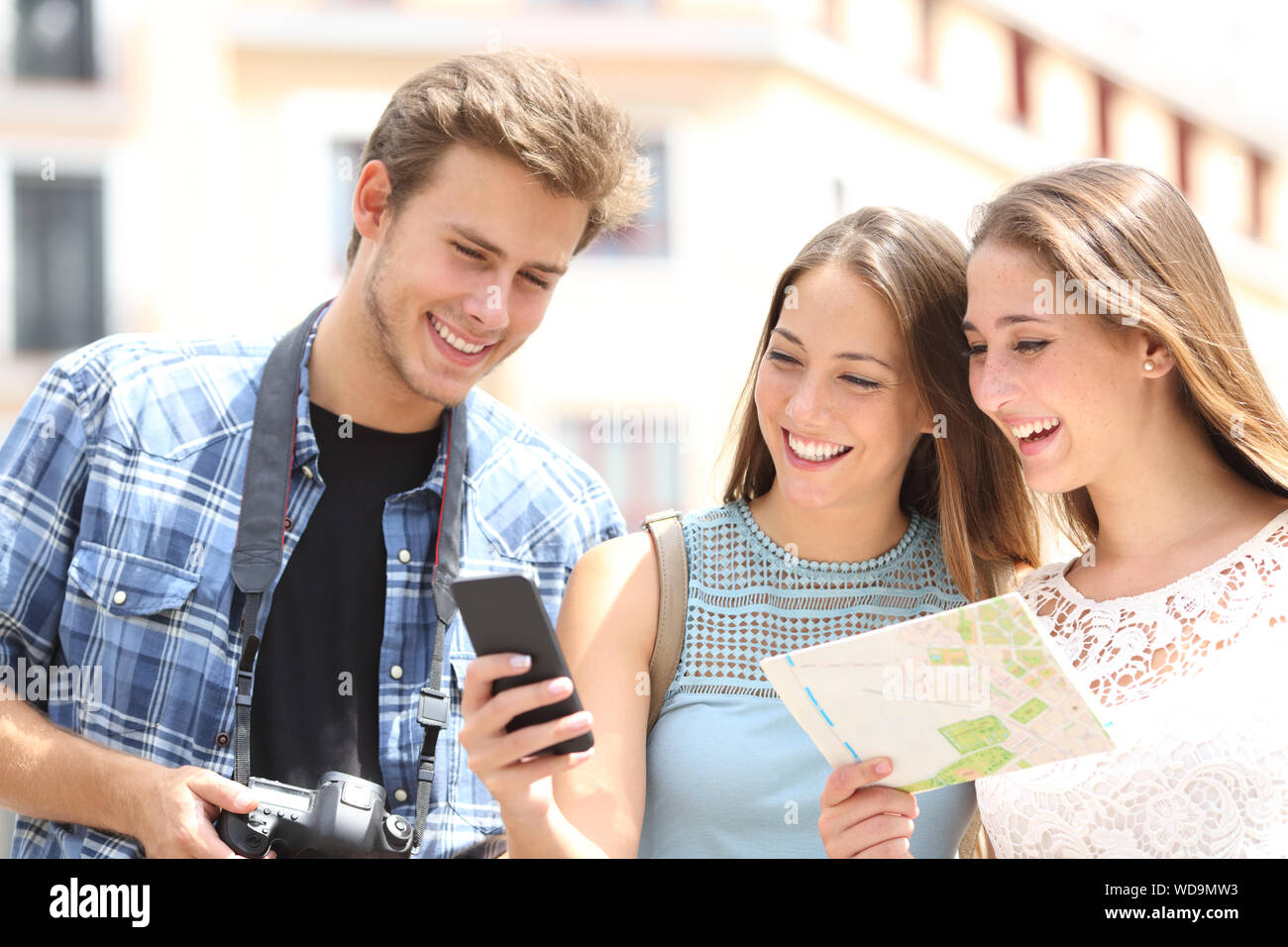 Three happy tourists traveling checking smart phone gps and map in the ...