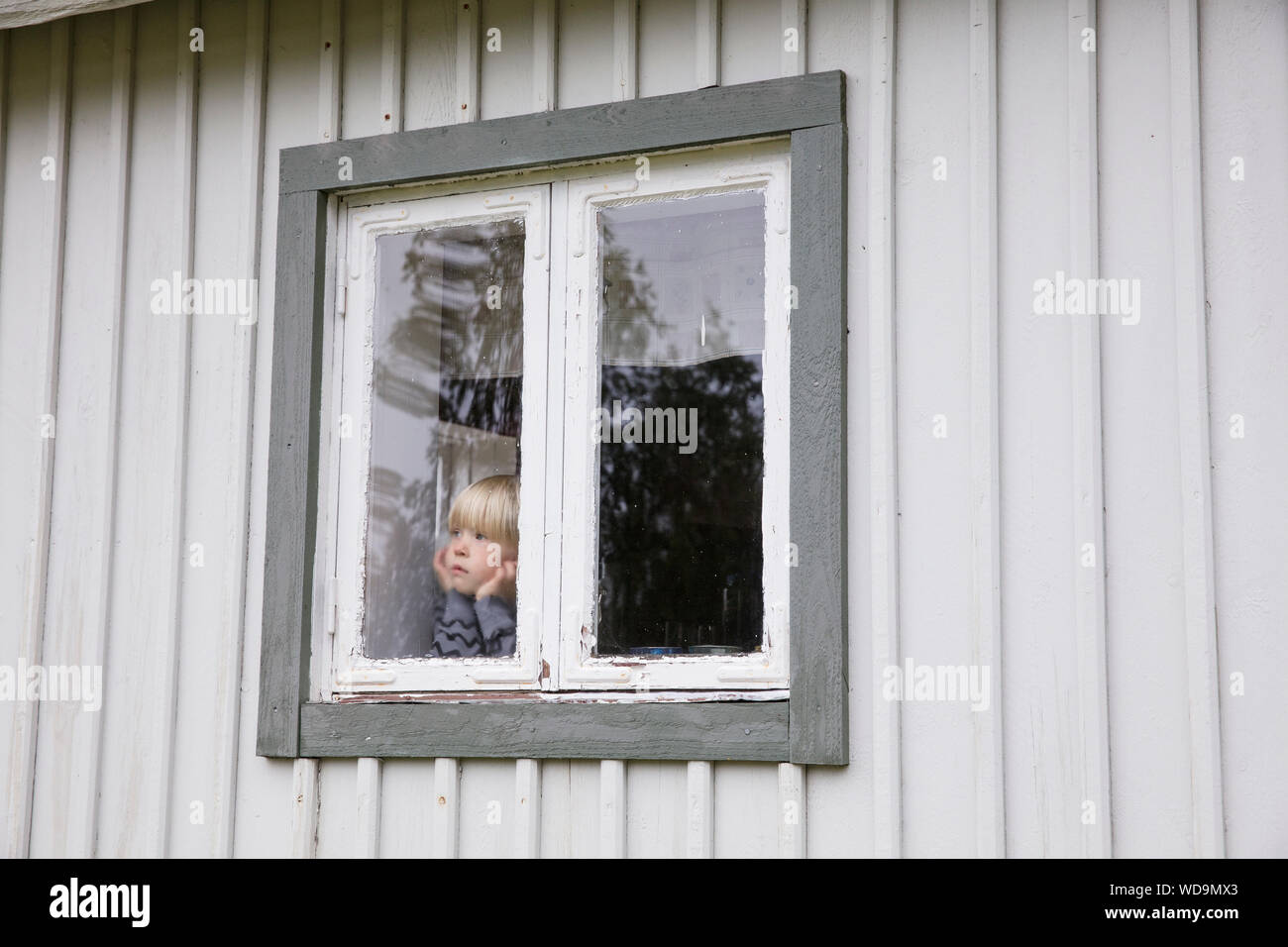 Boy in window of house Stock Photo - Alamy