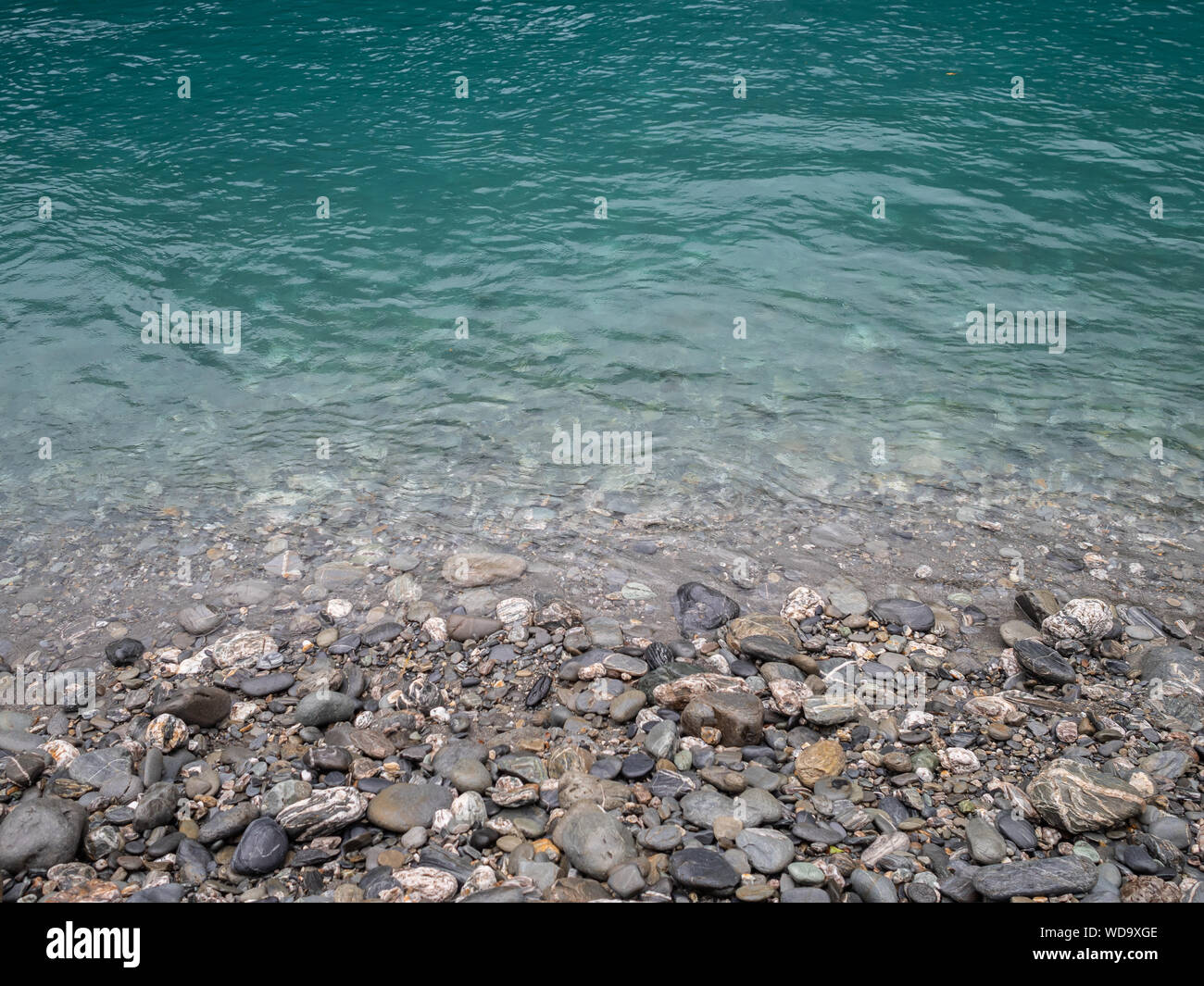 View of turquoise blue creek and stony shore Stock Photo - Alamy