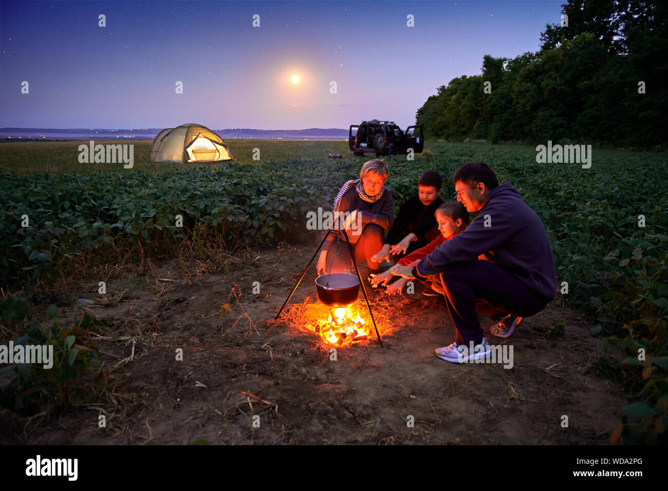 Family traveling and camping, twilight, cooking on the fire. Beautiful ...