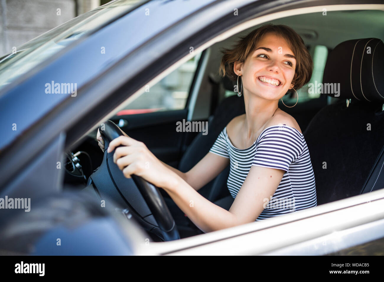 Smiling beautiful brunette woman driving a car Stock Photo - Alamy