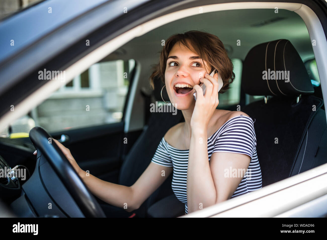 Driver woman driving a car distracted on the phone and looking at side ...