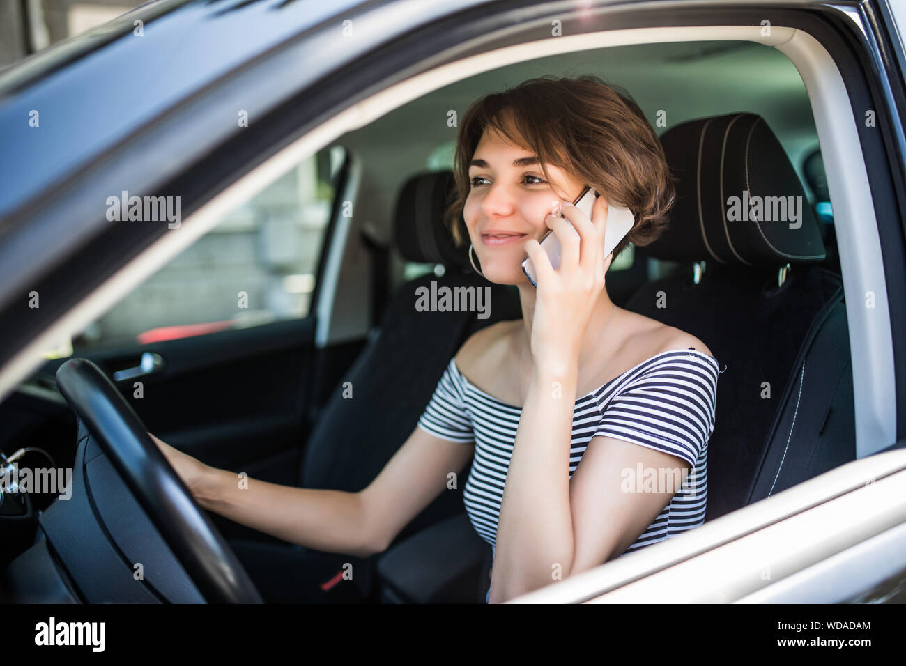 Young woman with telephone having phone conversation while driving car ...