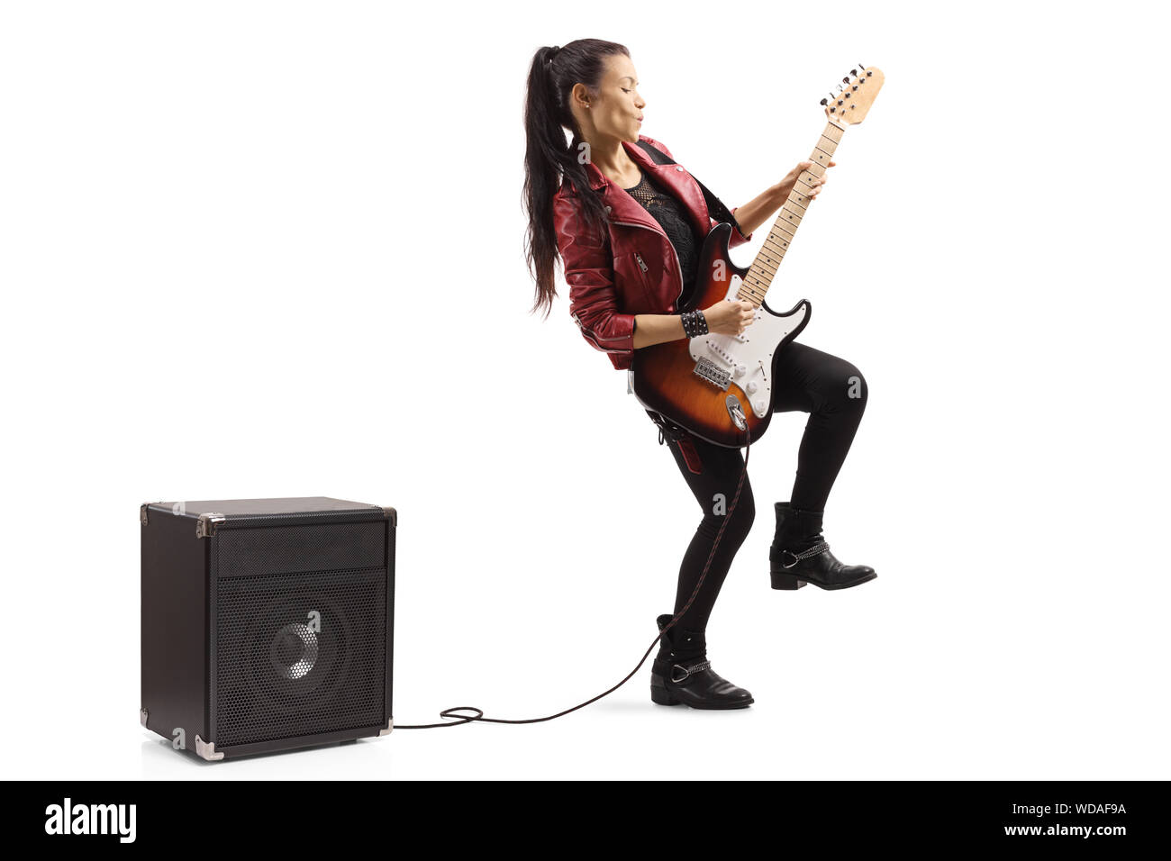 Full length shot of a young female guitarist playing a guitar plugged ...