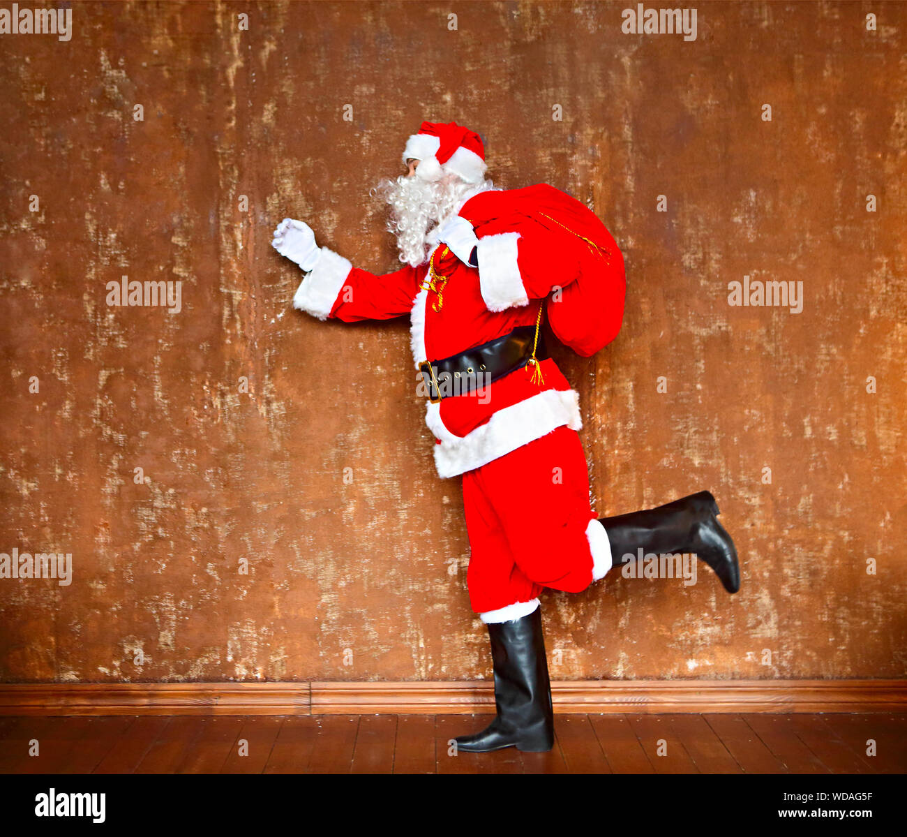 Santa Claus walking with the big red bag of the presents on the brown ...