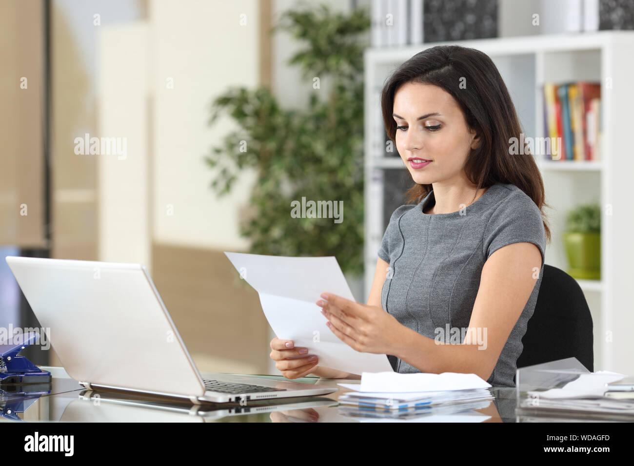 Serious office worker reading a paper letter in a desk Stock Photo - Alamy