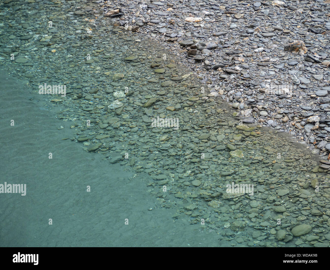 View of turquoise blue creek and stony shore Stock Photo - Alamy