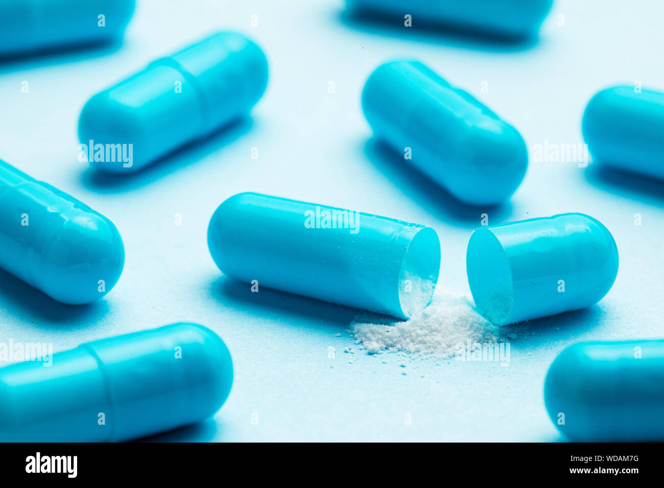 Blue tablets in capsules. One capsule is open. Blue background Stock ...