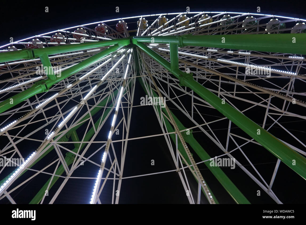 A Ferris wheel turns in the evening in the dark. The wheel is ...