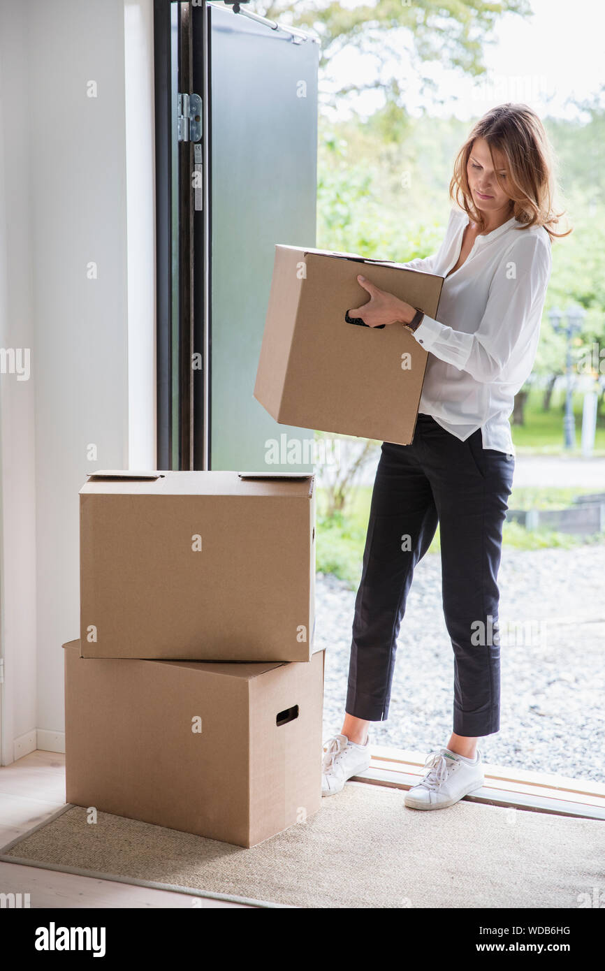 Woman carrying cardboard box into house Stock Photo - Alamy