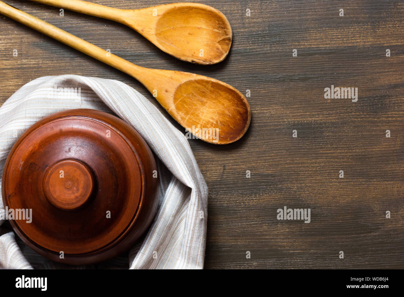 Top view of clay pot and wooden spoons on the wooden background with ...